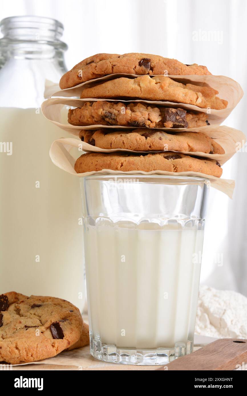Closeup of a stack of fresh baked cookies on top of a glass of milk ...