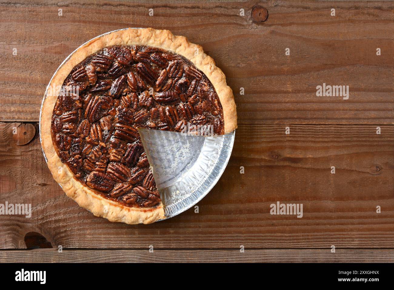 A Pecan pie with a slice cut out. Horizontal format on a rustic wood ...