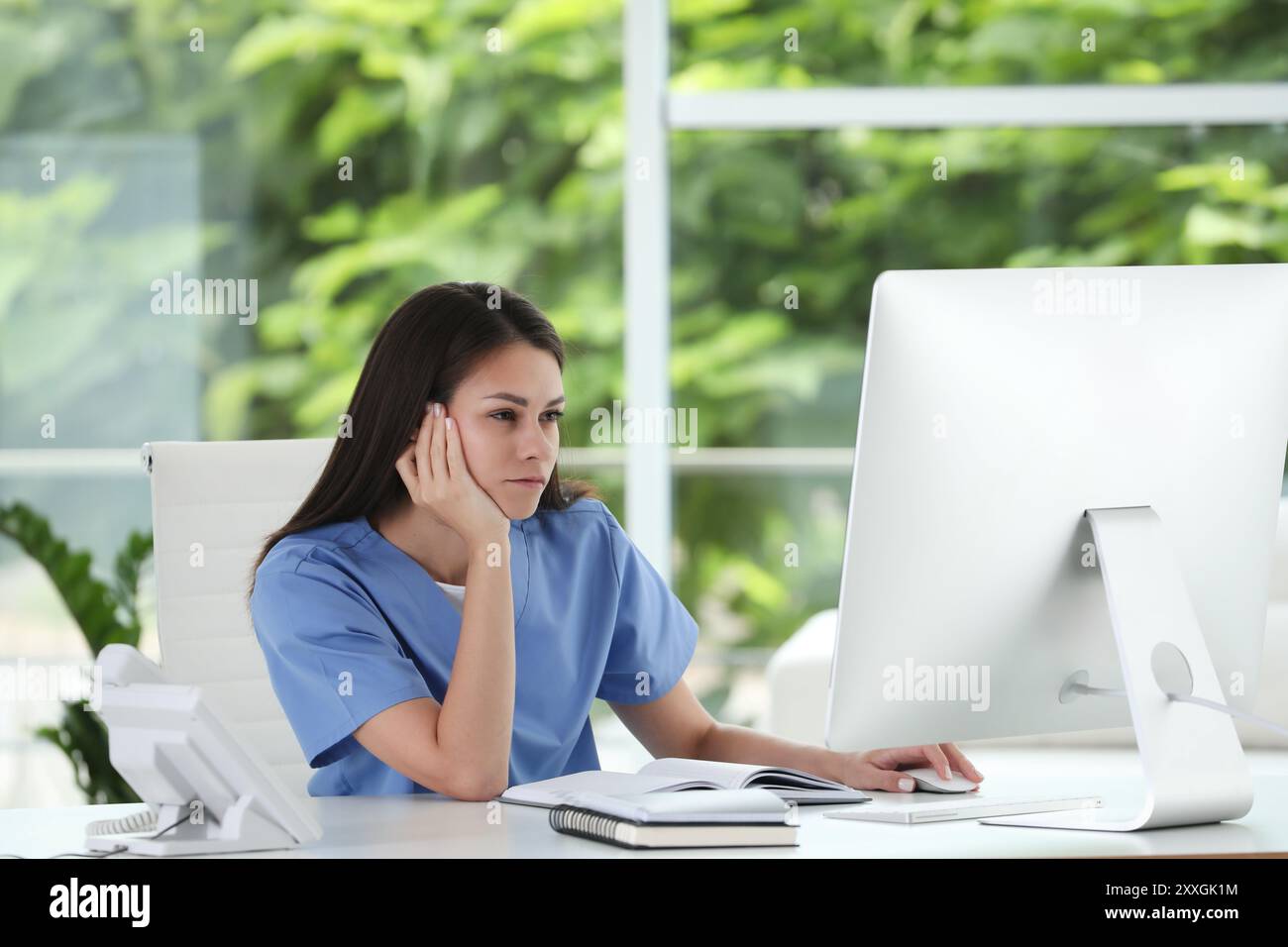 Beautiful nurse working with computer at table in hospital office Stock ...