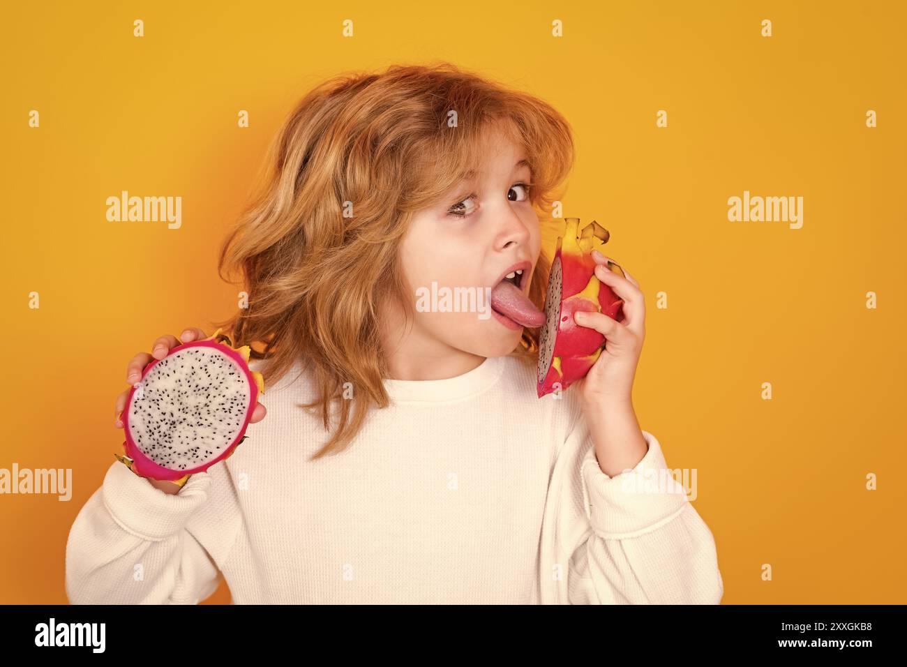 Kid eat dragon fruit in studio. Studio portrait of cute child with ...