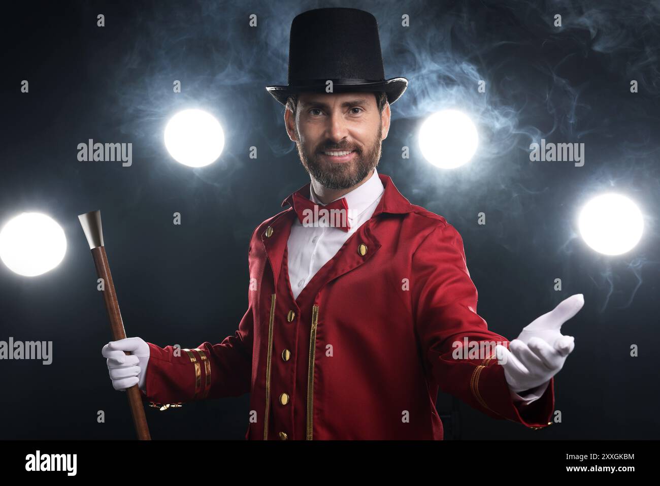 Portrait of showman in red costume, cane and hat on black background ...
