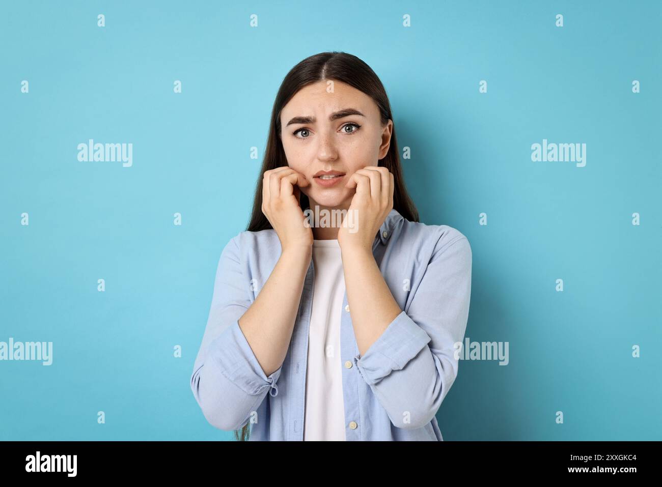 Portrait of scared woman on light blue background Stock Photo - Alamy