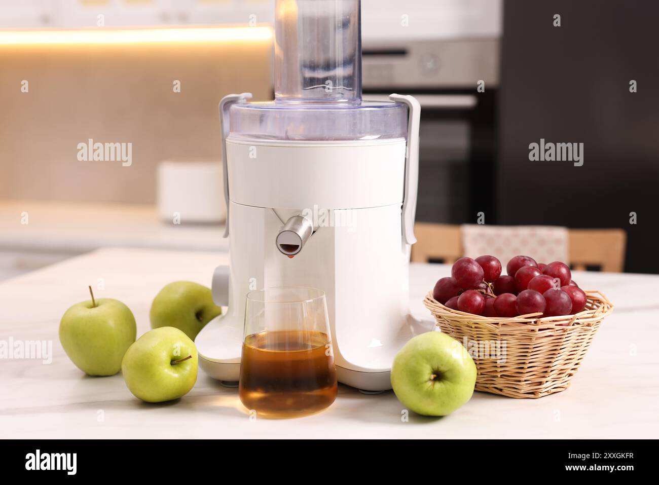 Modern juicer, fresh fruits and glass on white marble table in kitchen ...