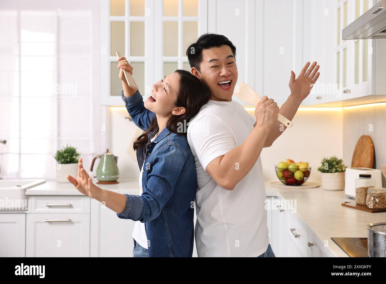 Happy lovely couple singing together while cooking in kitchen Stock ...