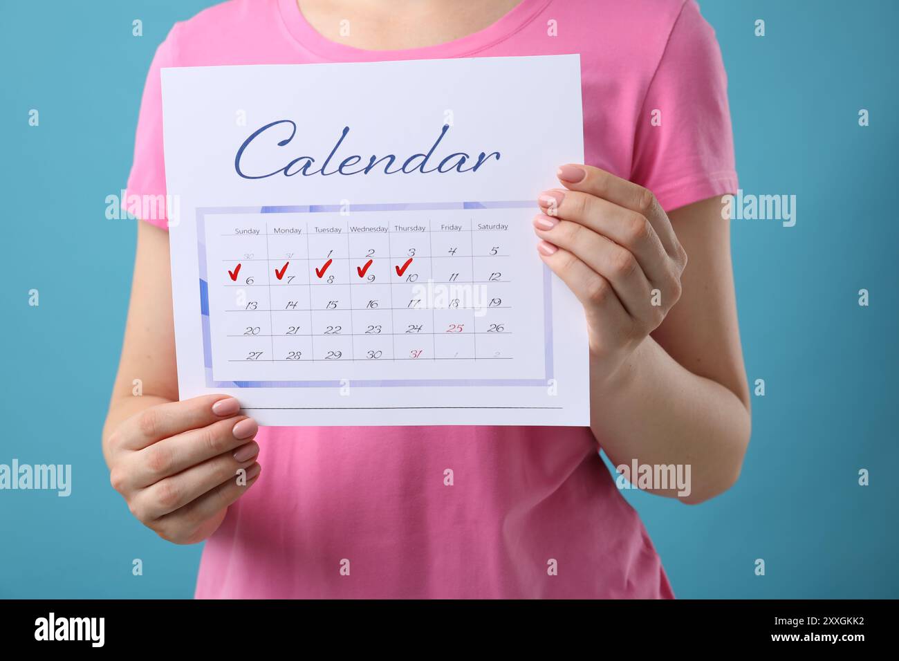 Woman holding calendar with marked menstrual cycle days on light blue ...