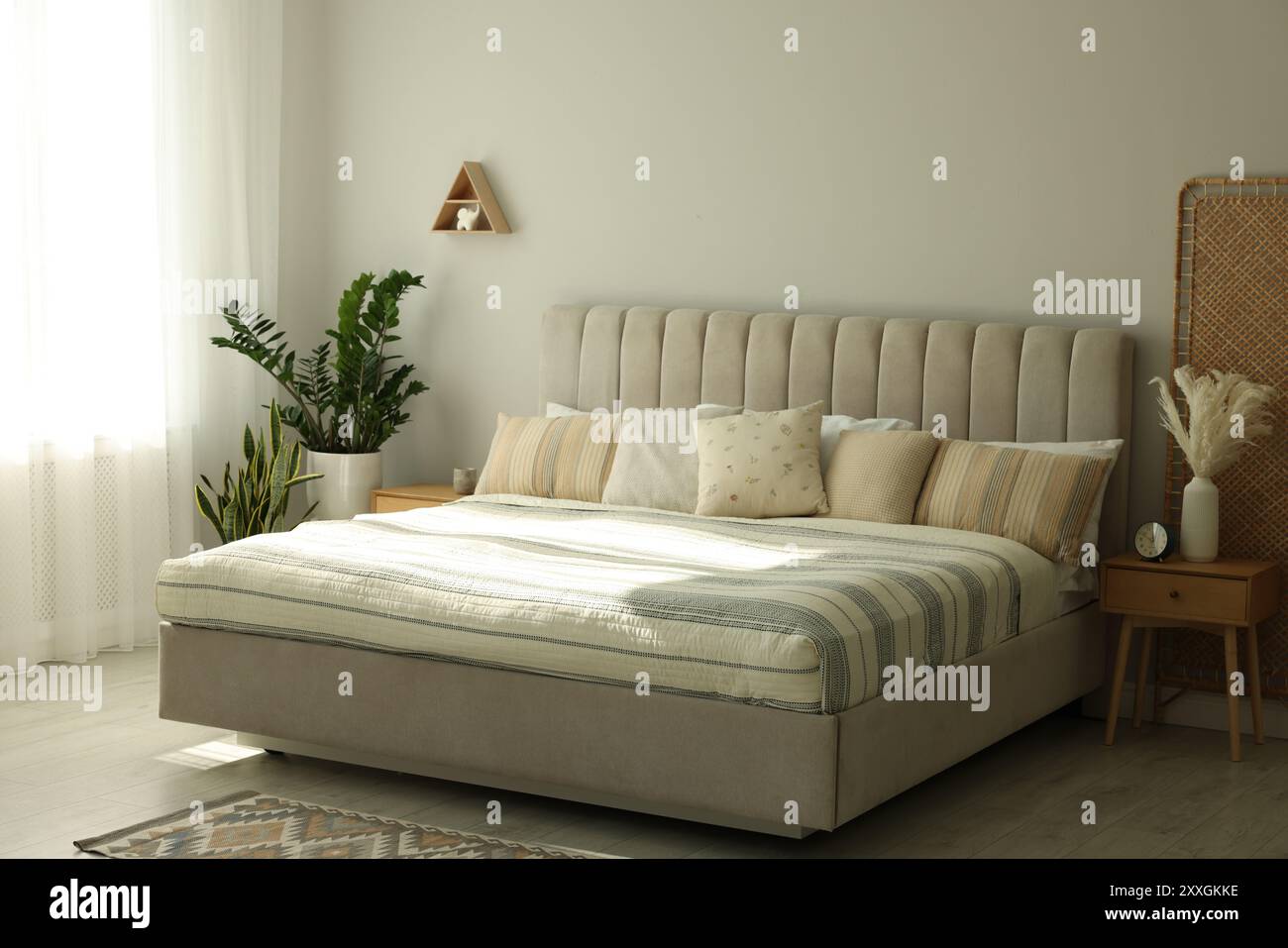 Large bed, houseplants and bedside table in stylish room Stock Photo ...