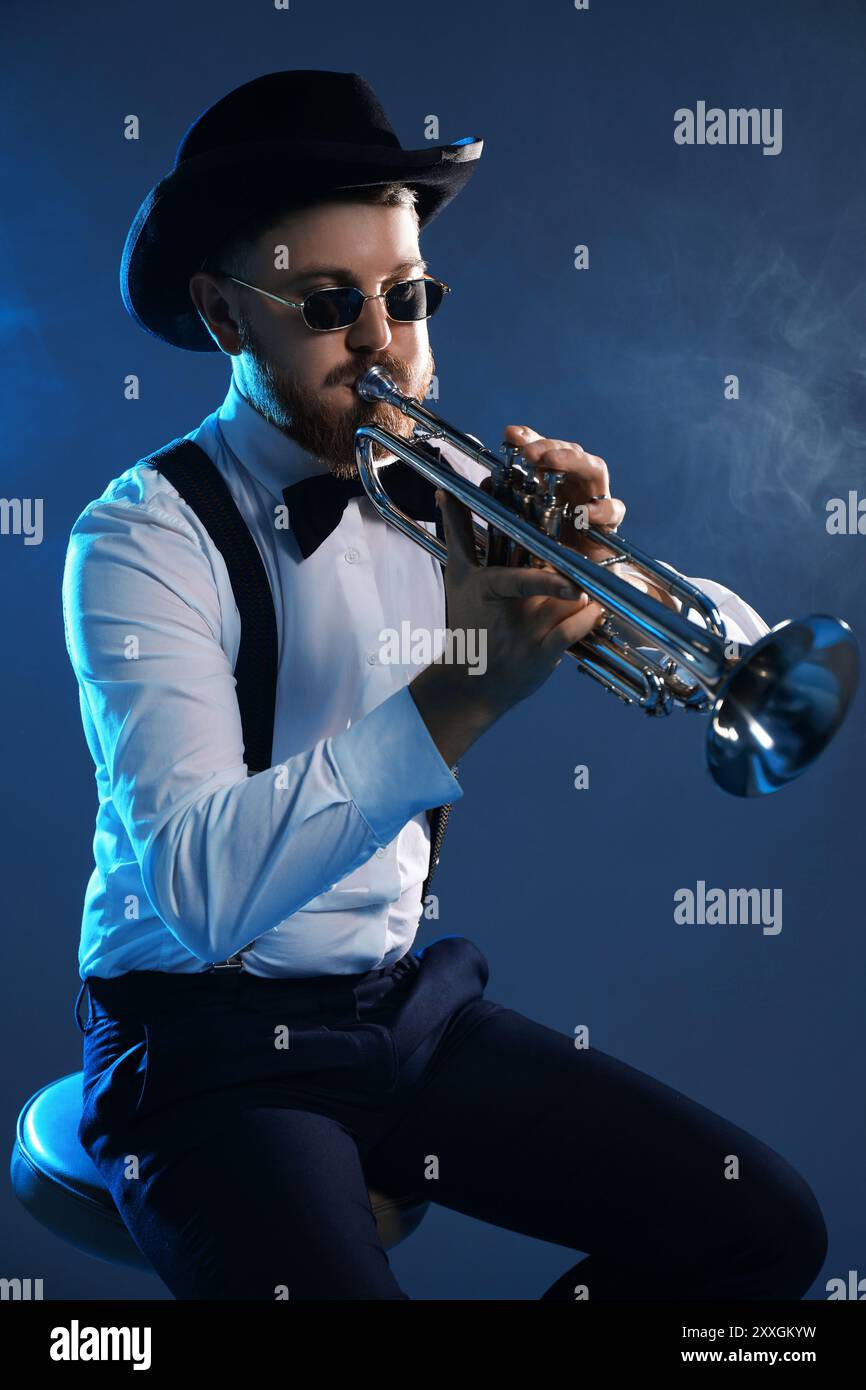 Professional musician playing trumpet on dark background with smoke ...