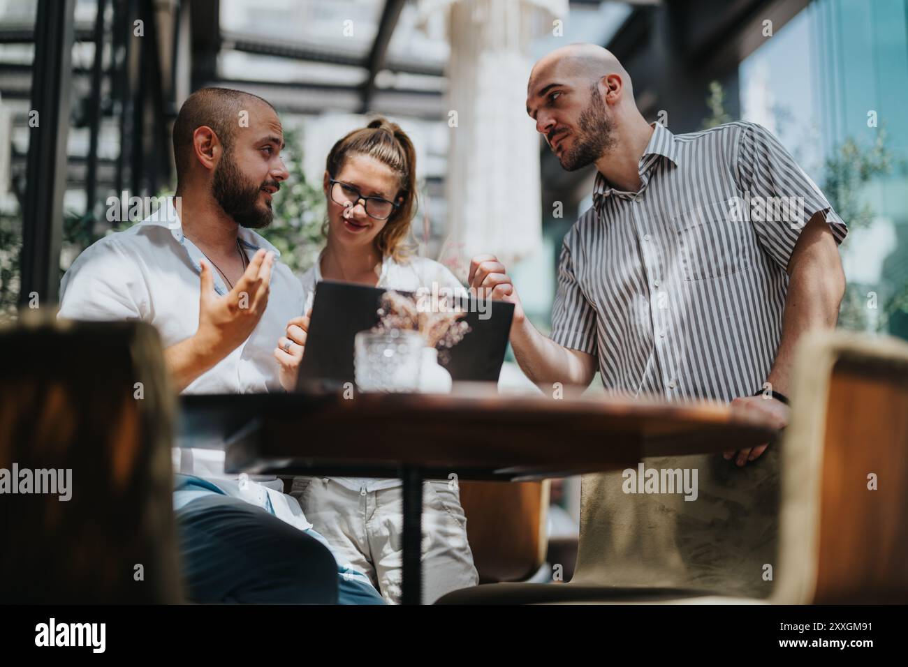 Business workers collaborating on a project in coffee bar ...
