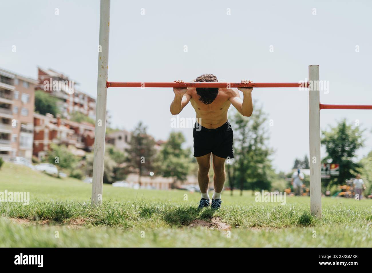 Fit man exercising in nature doing pull-ups on outdoor gym equipment ...