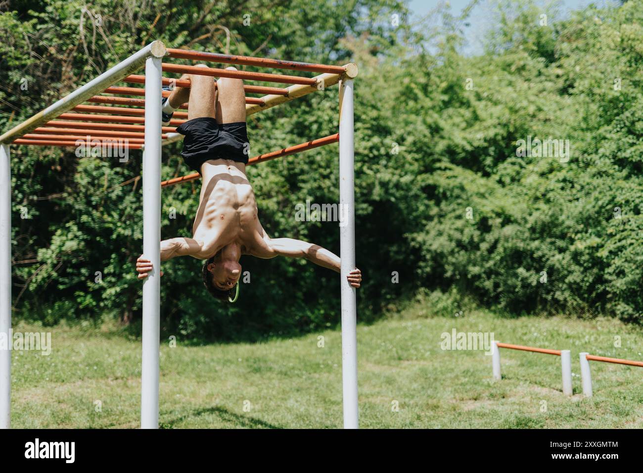 Fit male athlete working out in park, performing calisthenics on monkey ...
