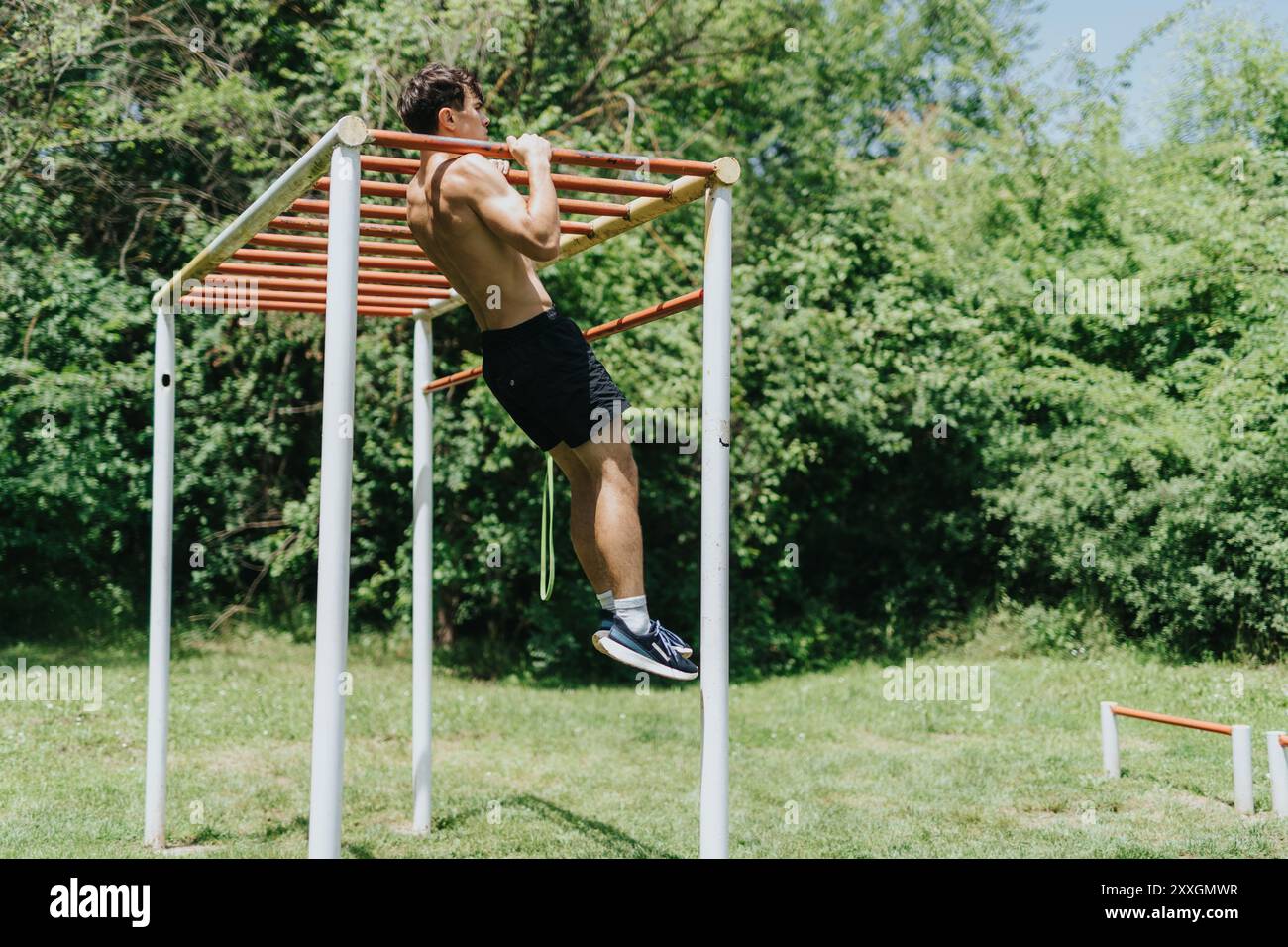 Fit male athlete performing pull-ups on monkey bars in a park Stock ...