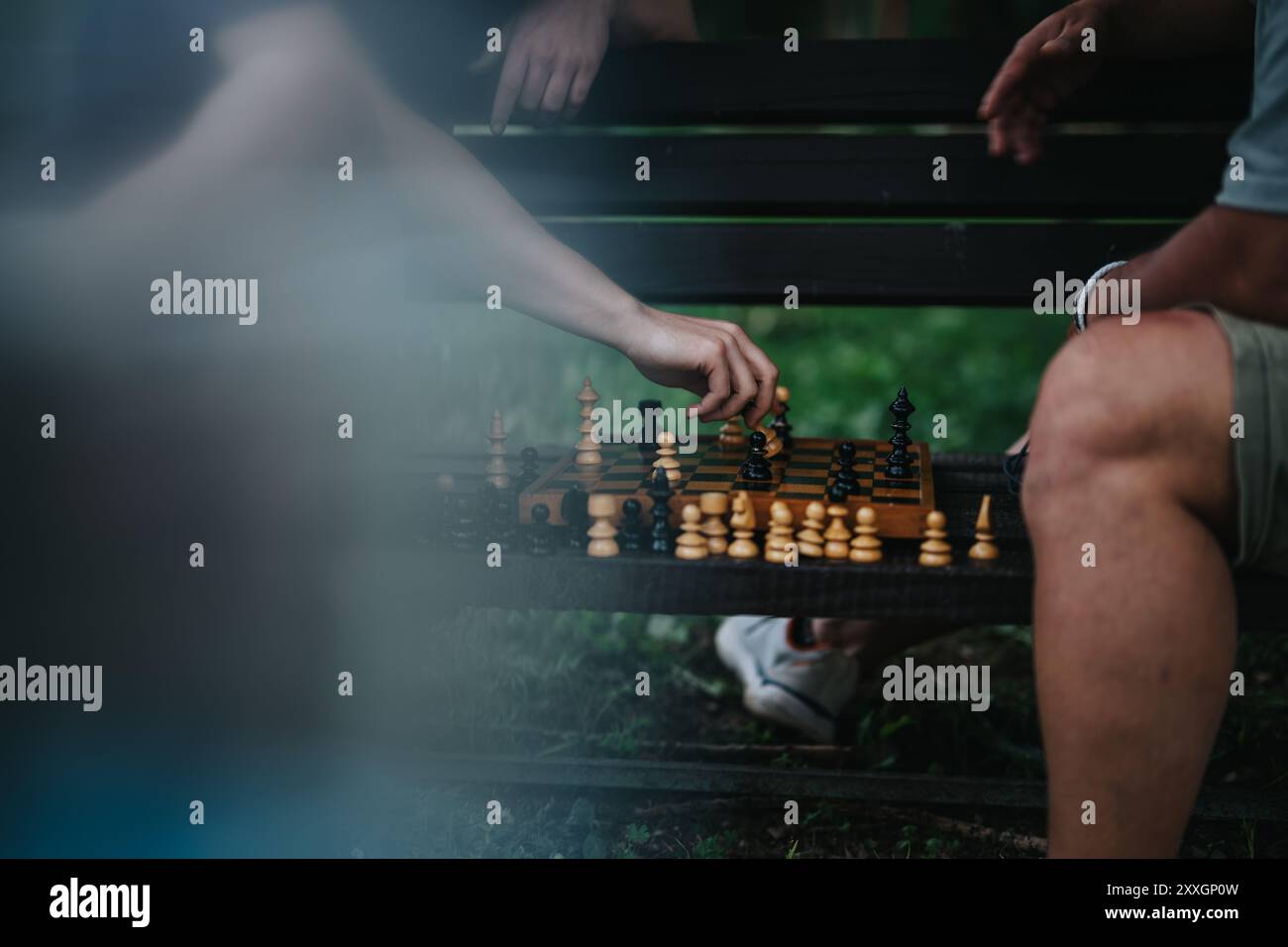 Two people playing chess on a park bench outdoors Stock Photo - Alamy