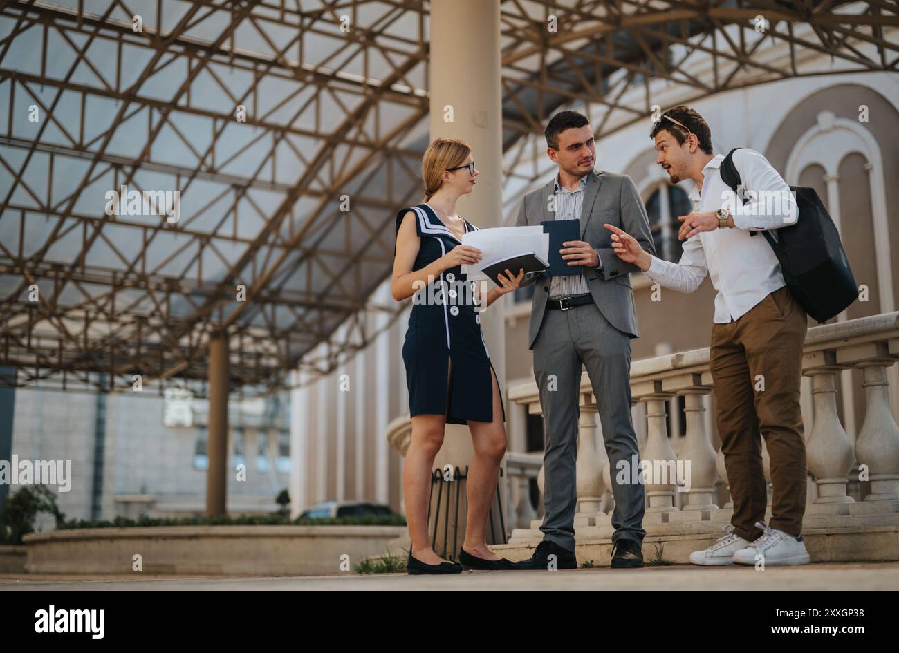 Professional team discussing a project outdoors under a modern ...