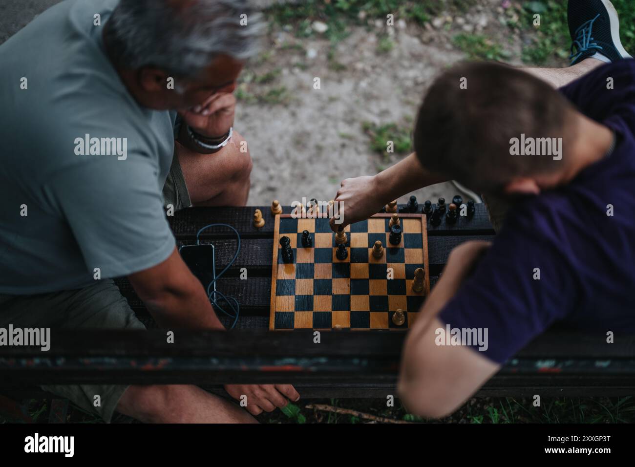 Top view of two people engaged in an intense game of chess on a wooden ...