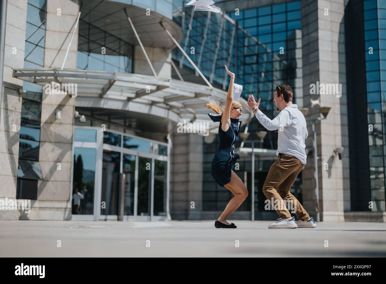Excited business professionals celebrating success outside modern ...
