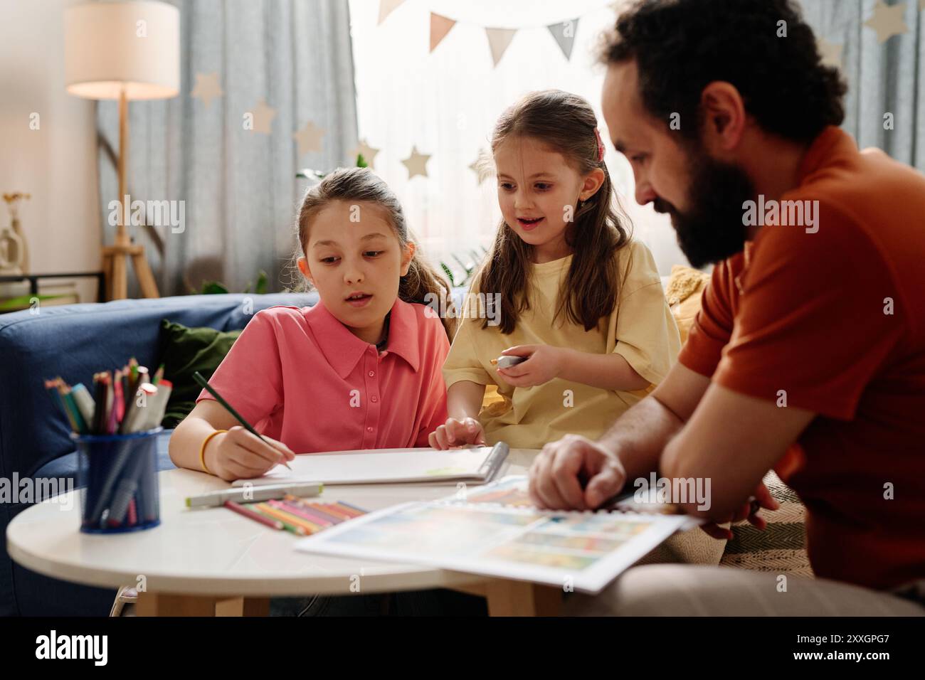 Teacher engaging with two girls doing homework at home environment ...