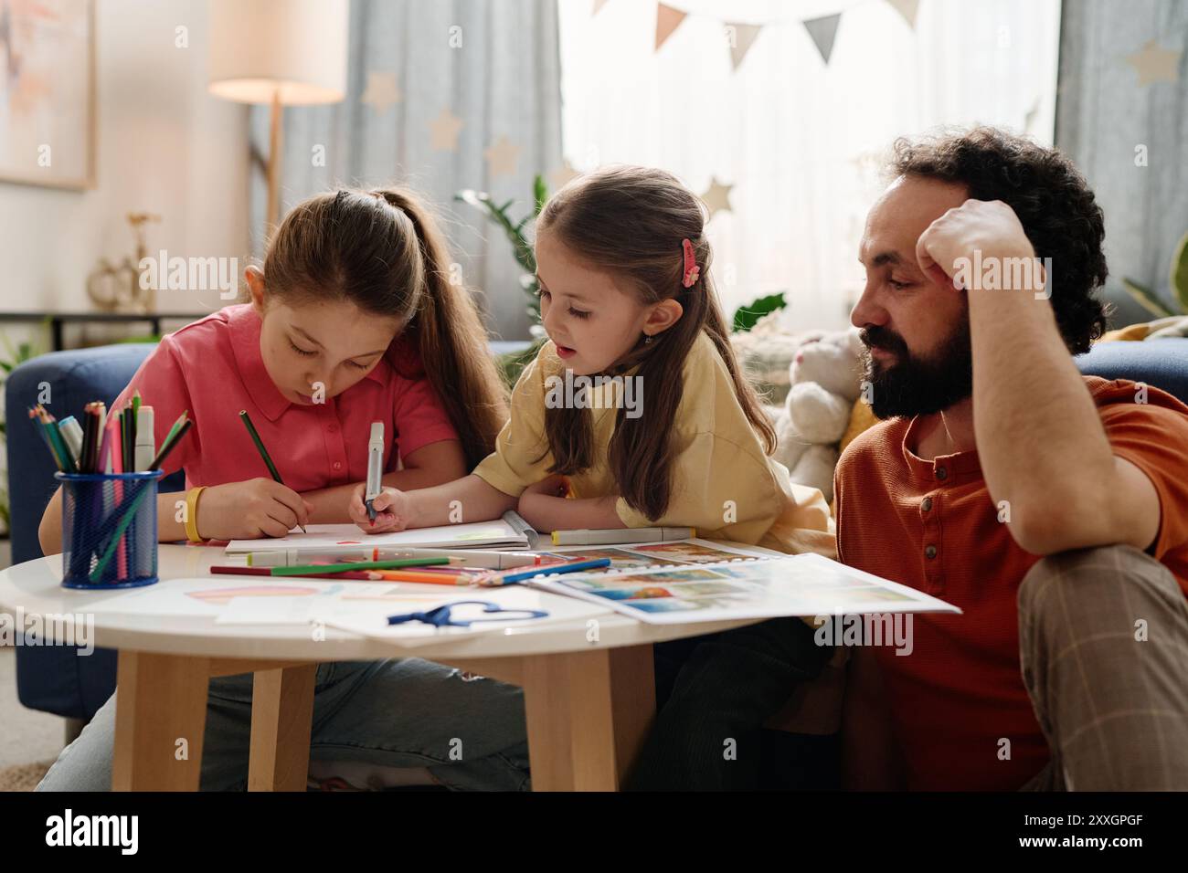 Parent sitting at table with two kids engaging in drawing and coloring ...