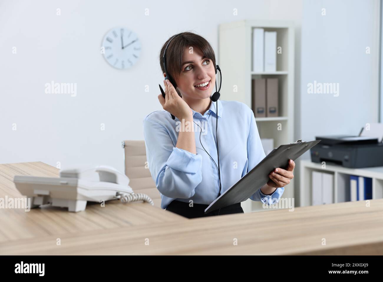 Professional receptionist working at wooden desk in office Stock Photo ...