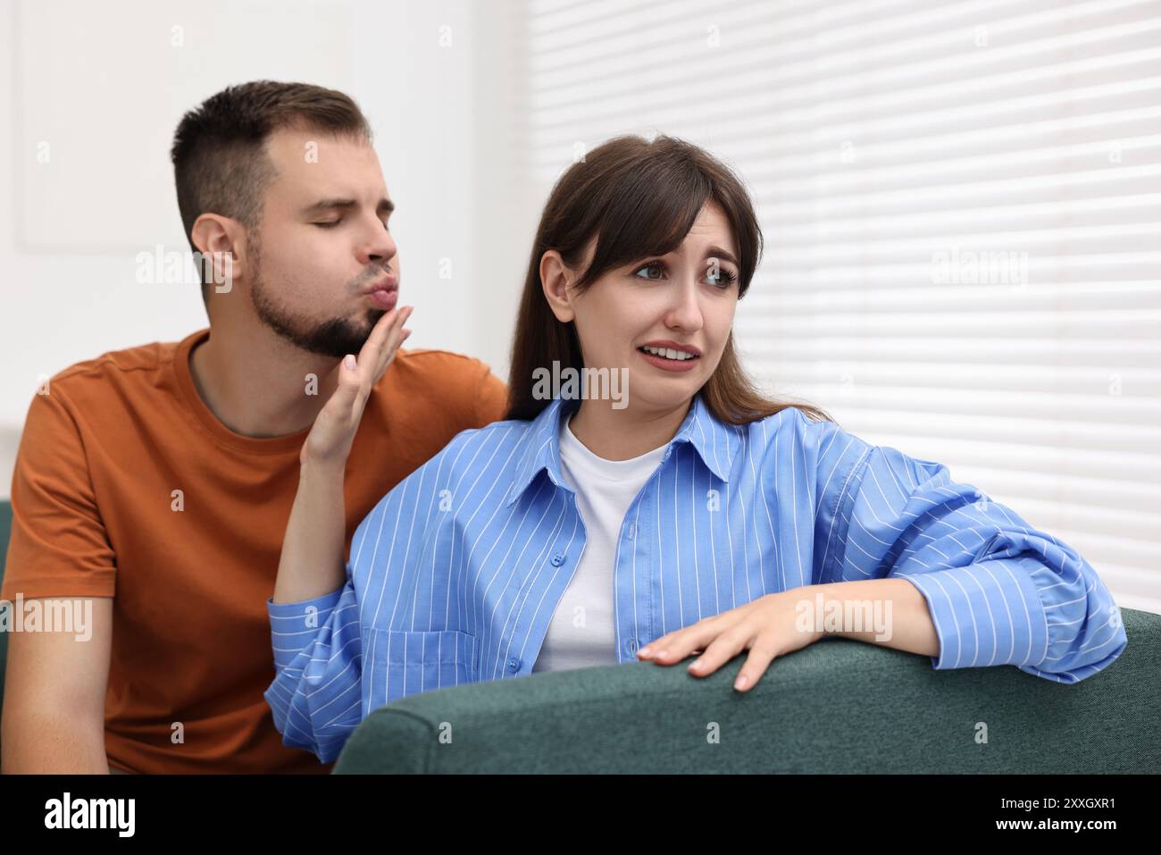 Embarrassed woman refusing from man's kiss at home Stock Photo - Alamy