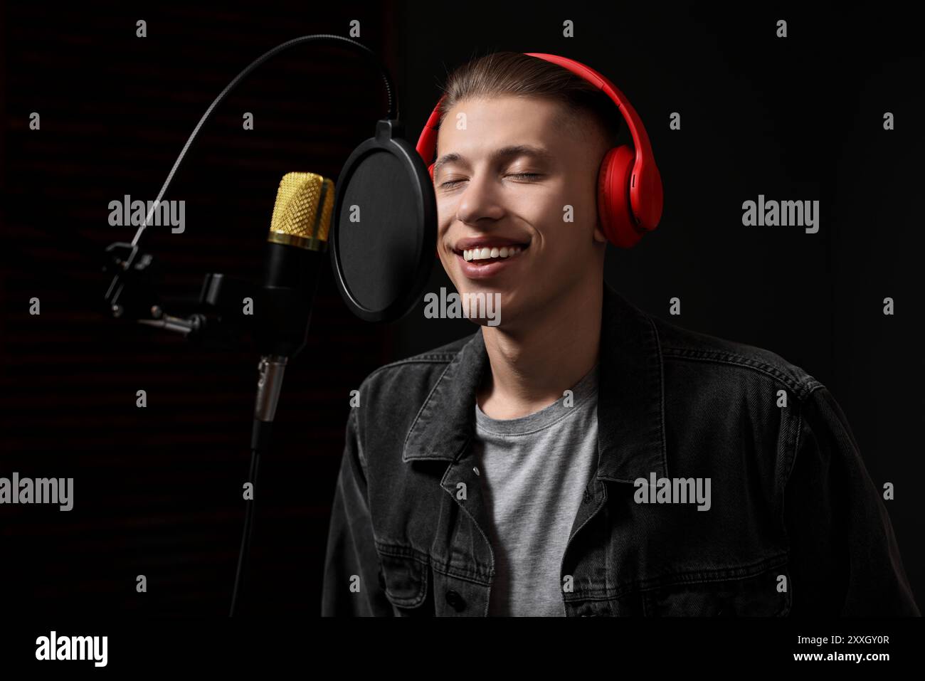 Vocalist with headphones singing into microphone in professional record ...