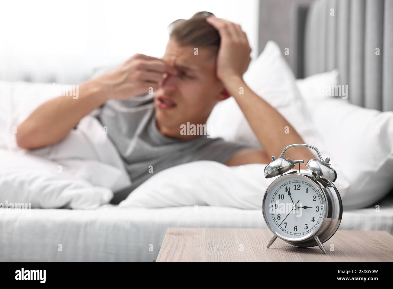 Man waking up in bedroom at lunch time, focus on alarm clock Stock ...
