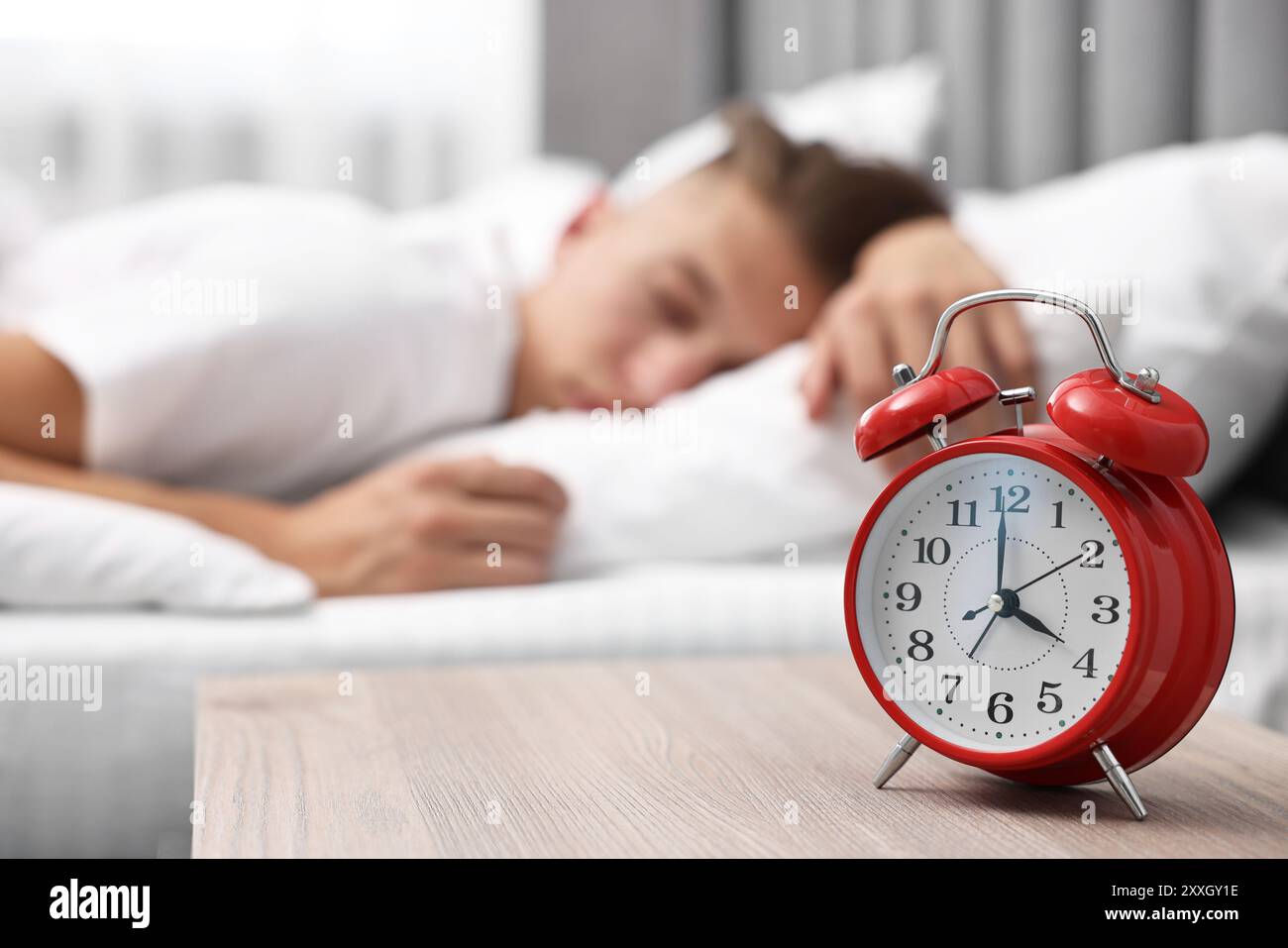 Man sleeping in bed at lunch time, focus on alarm clock Stock Photo - Alamy