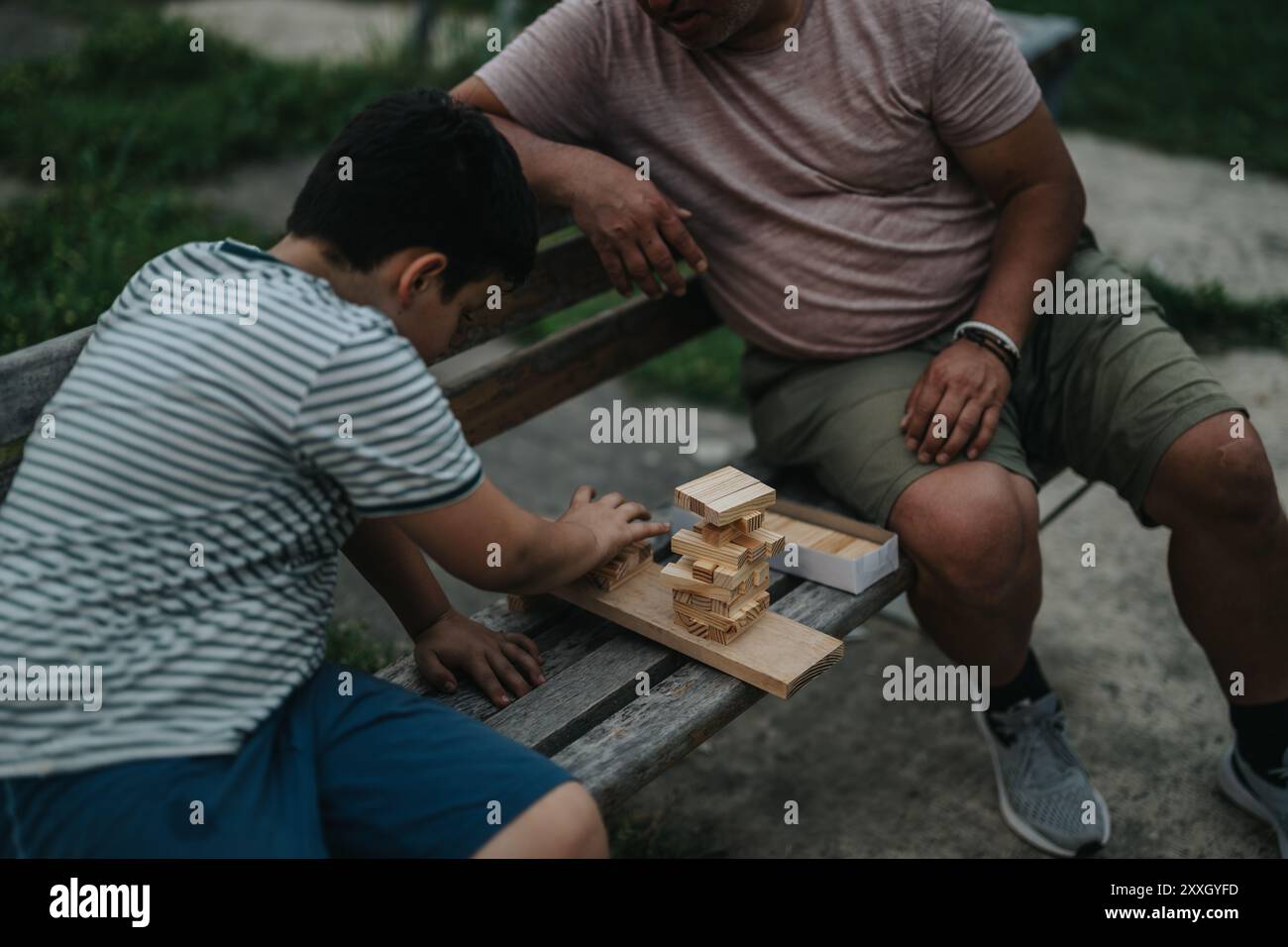 Father and son playing a wooden block game on a park bench Stock Photo ...