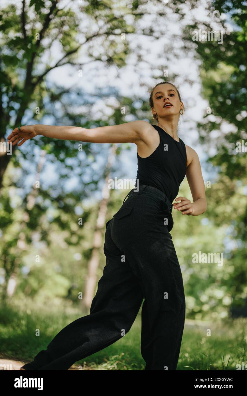 Lovely girl dancing and performing modern dance in nature surrounded by beautiful trees Stock ...