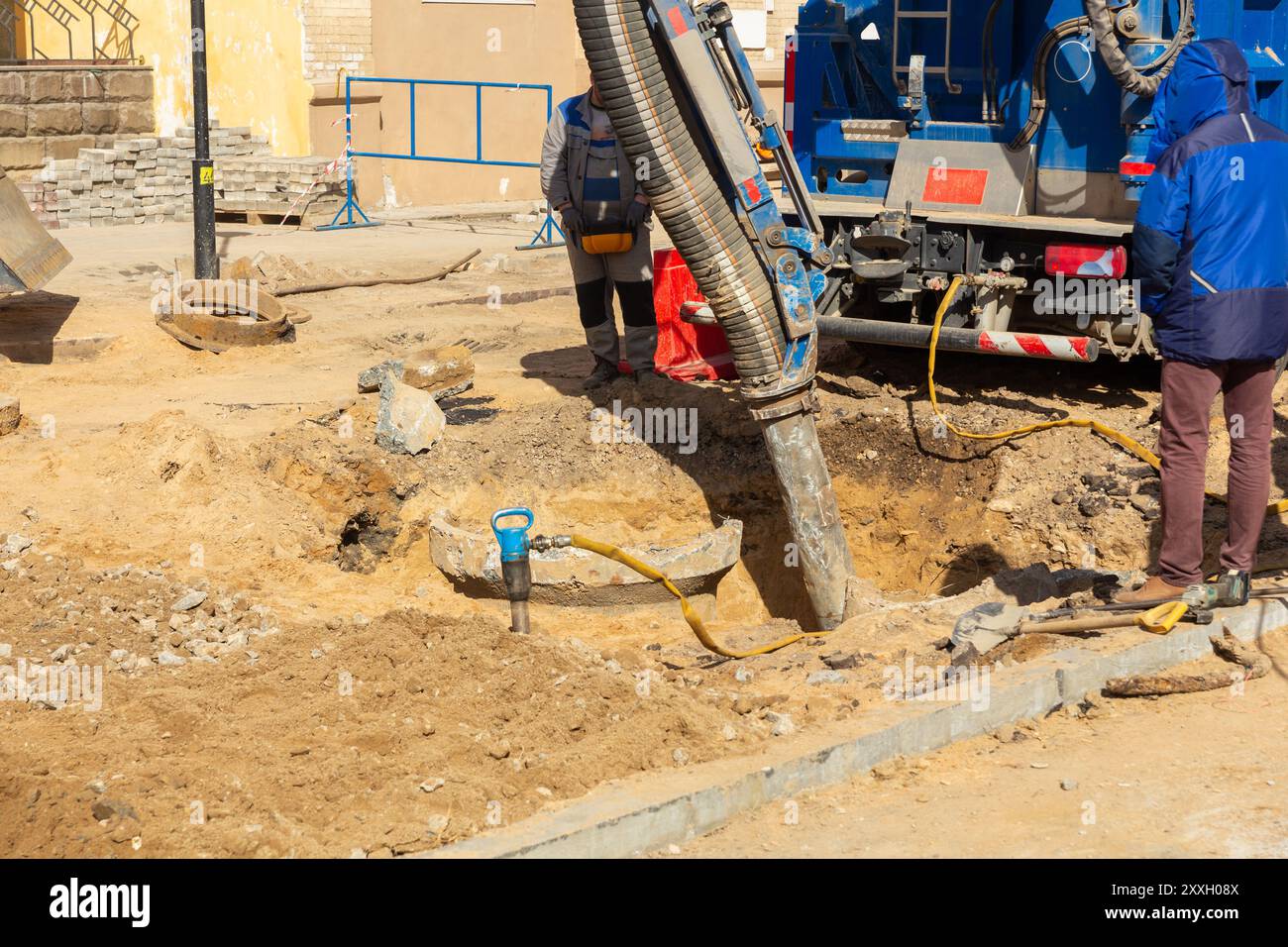 Workers use a suction excavator based on a truck to sample soil in a ...