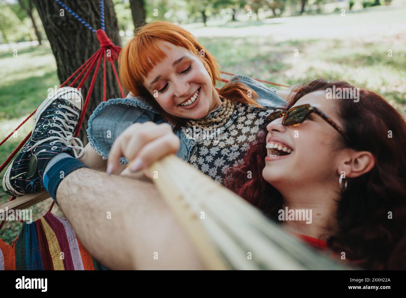 Happy friends laughing while relaxing in a hammock on a sunny day in ...
