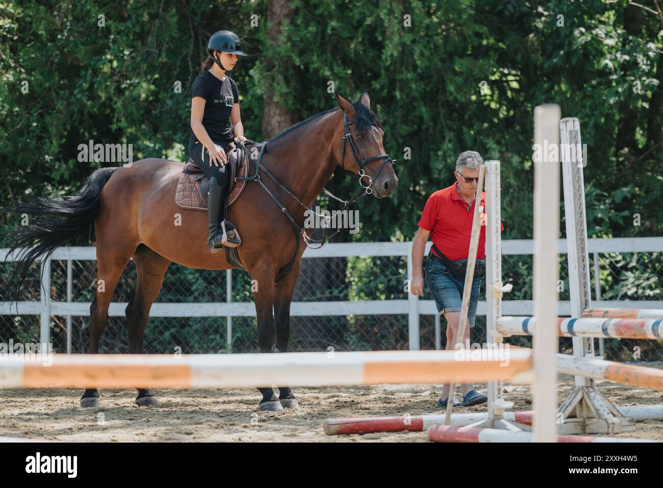 Young rider on horse receiving guidance during equestrian training ...