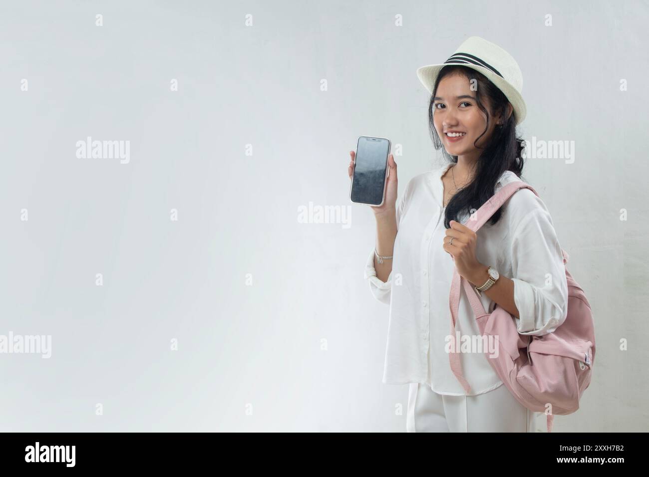 Asian woman wearing straw hat and backpack holding black screen ...