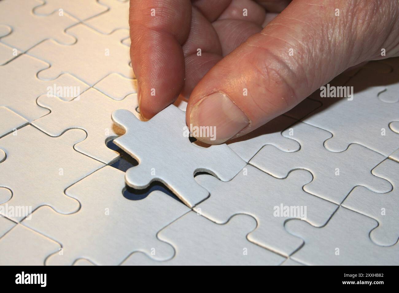Hand with puzzle piece on jigsaw puzzle Stock Photo - Alamy