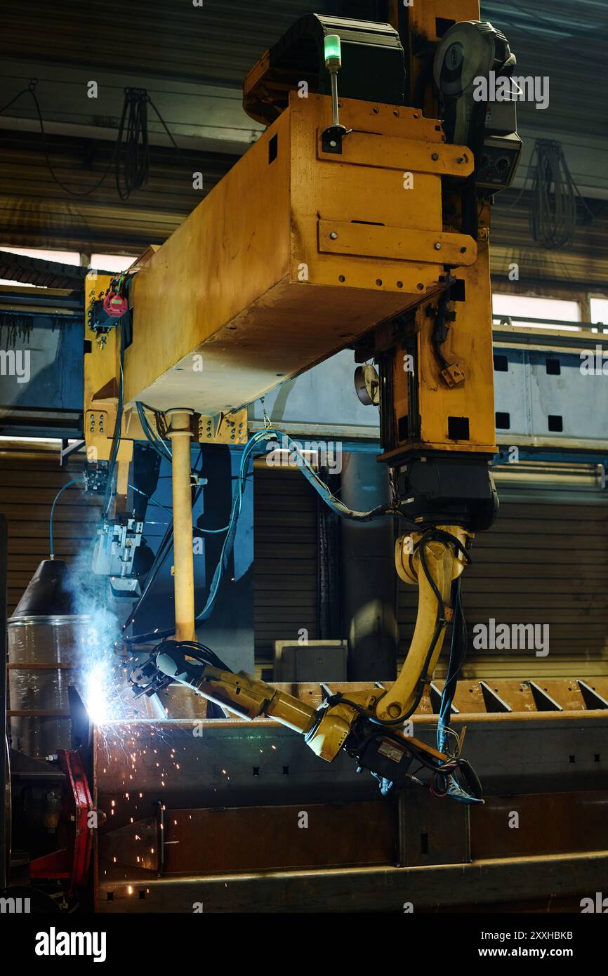 Industrial robotic arm welding metal component in factory. Sparks ...