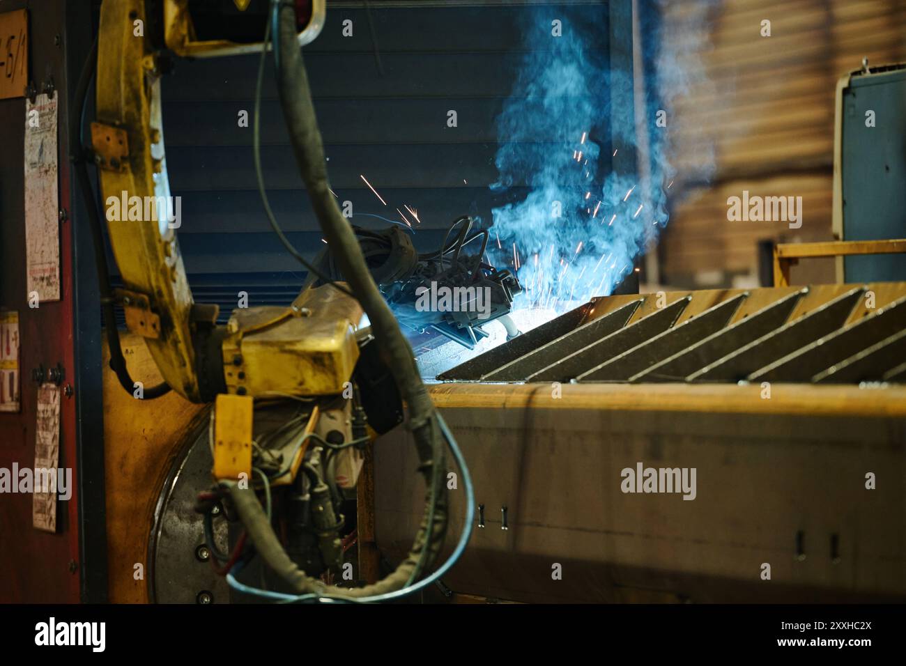 Worker conducting welding task with industrial machinery surrounded by ...
