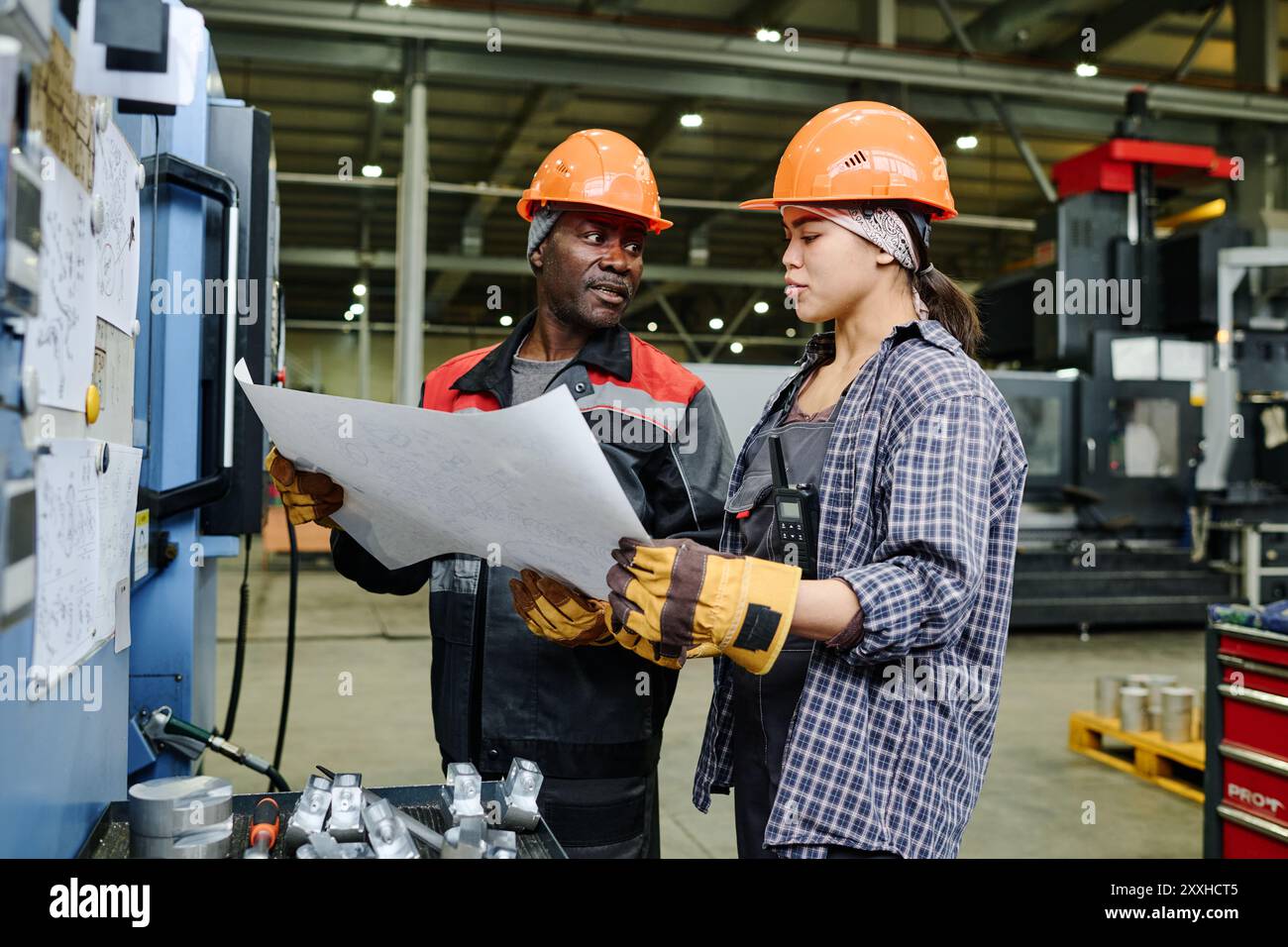 Multiracial male and female construction workers reviewing a blueprint in a well-lit ...