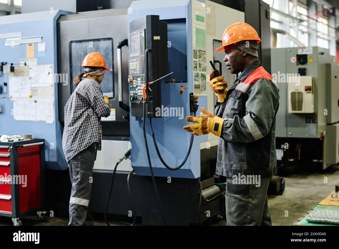 Workers in an industrial setting overseeing machinery operation and ...