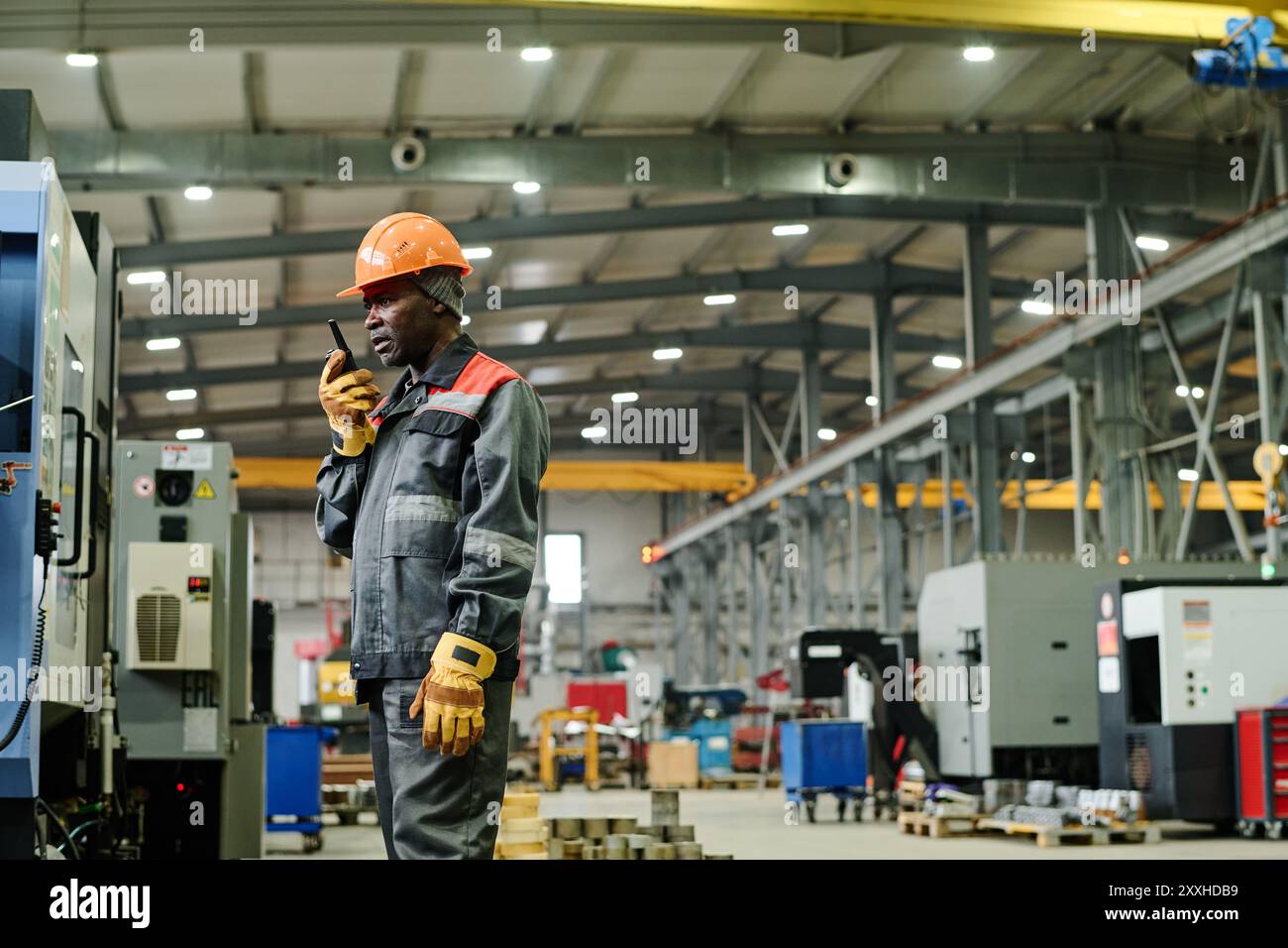 Caucasian factory worker operating heavy machinery in spacious ...