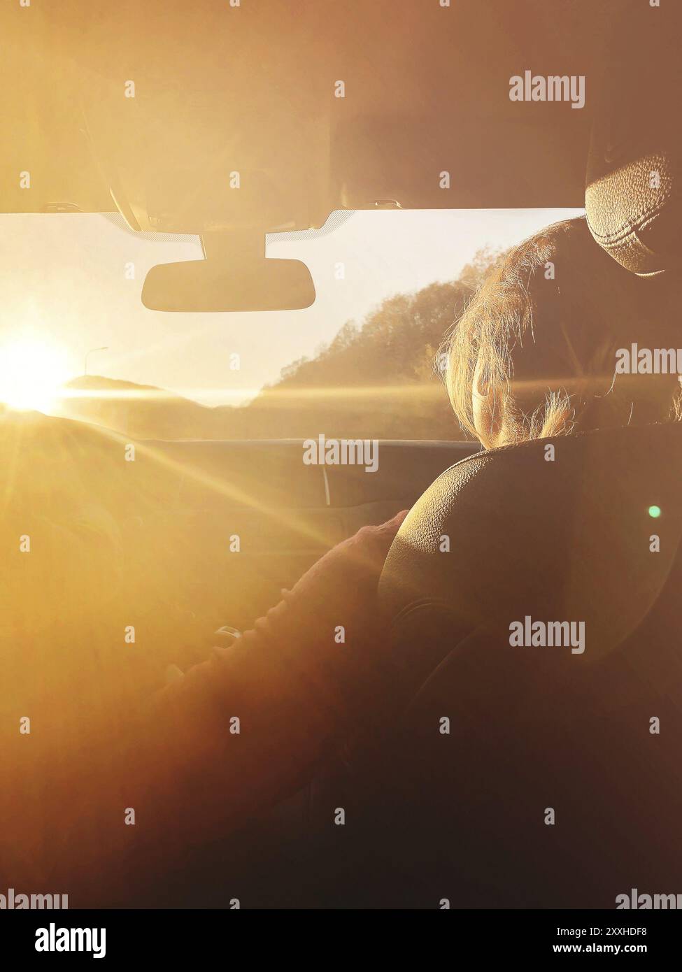 Back view of female sitting on passenger seat in automobile while ...