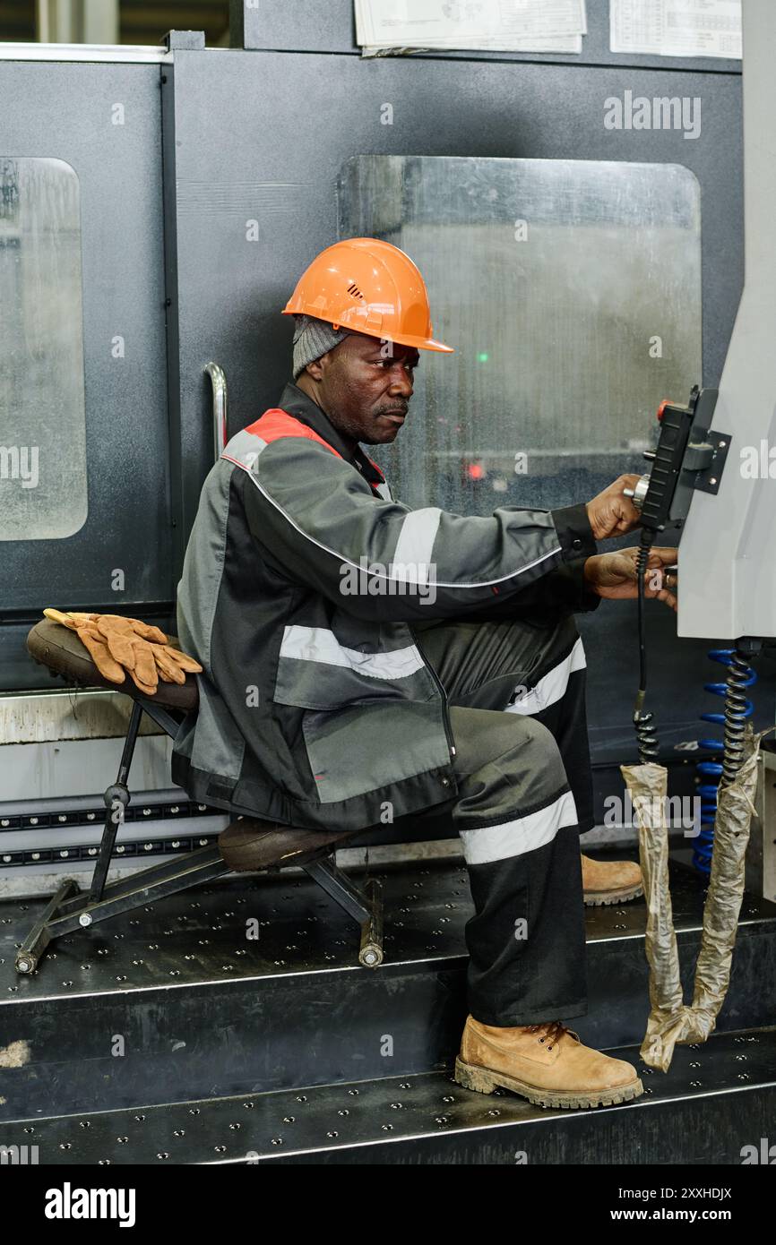 African American worker operating heavy machinery while wearing safety ...