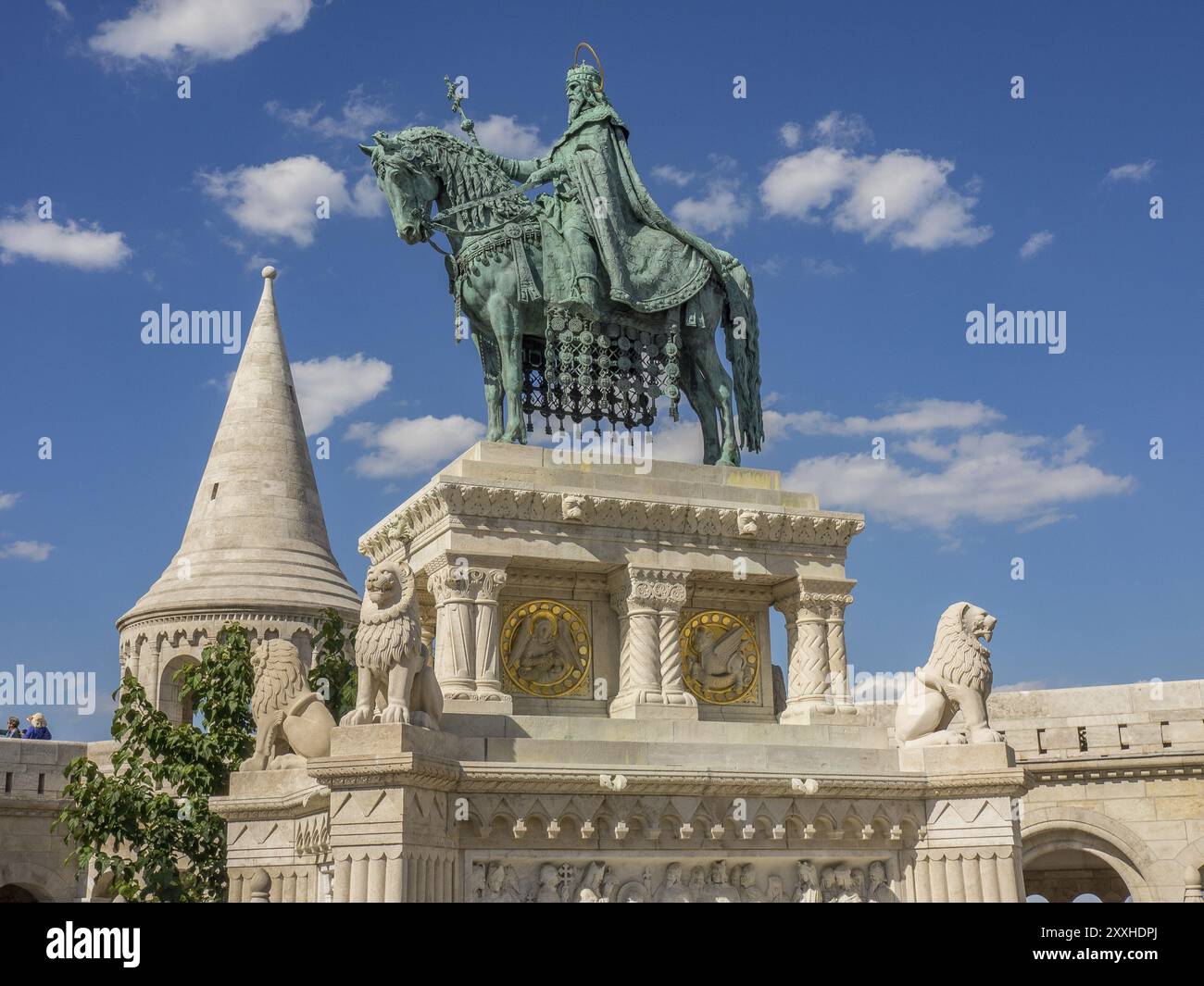 Equestrian statue on an ornate pedestal in front of towers under a blue ...
