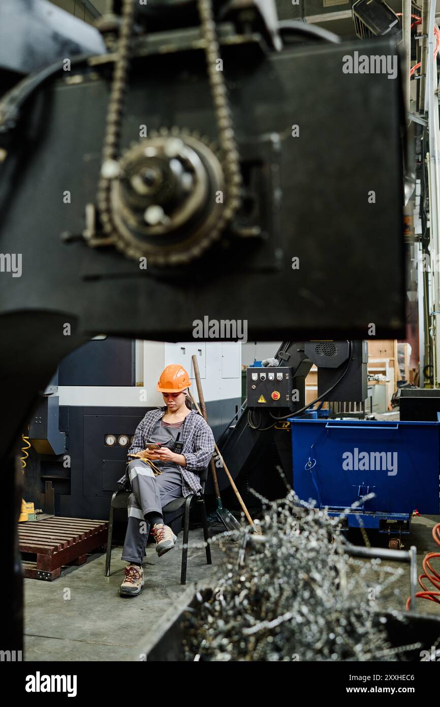 Engineer sitting on chair, wearing safety helmet, operating machinery ...