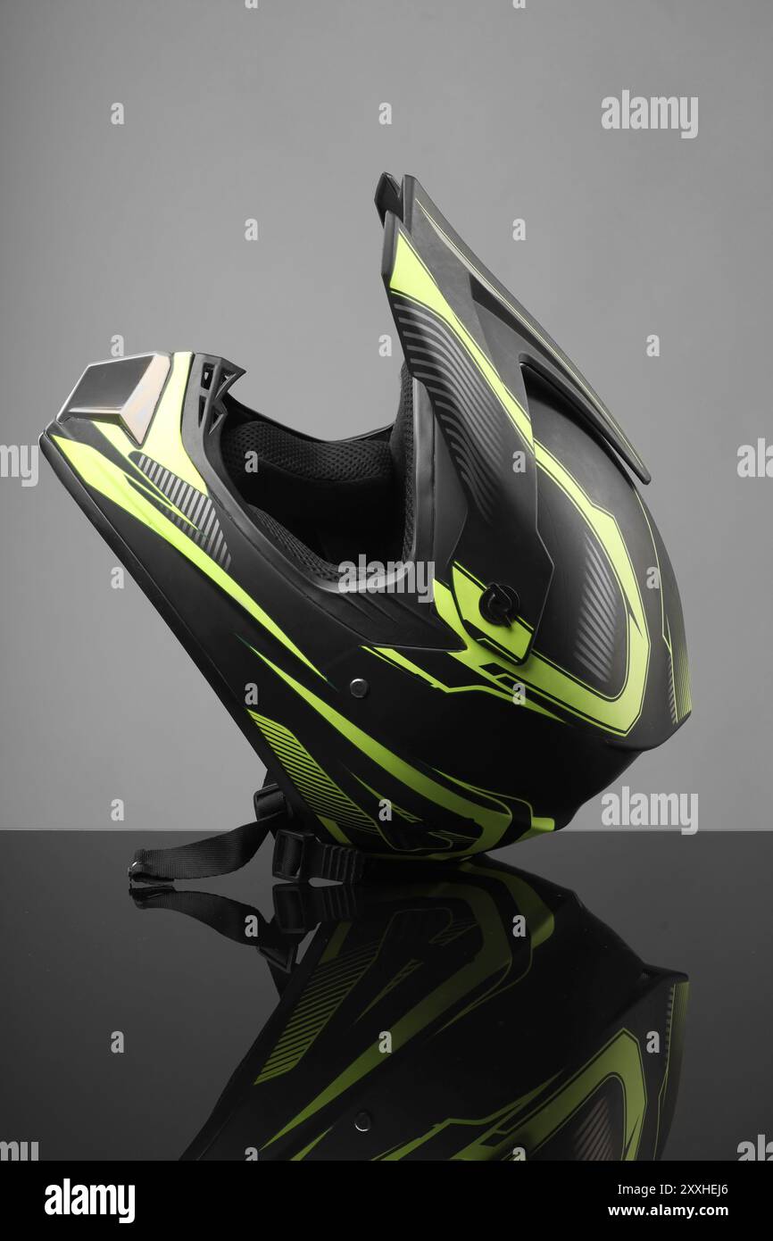 Modern motorcycle helmet with visor on mirror surface against light ...