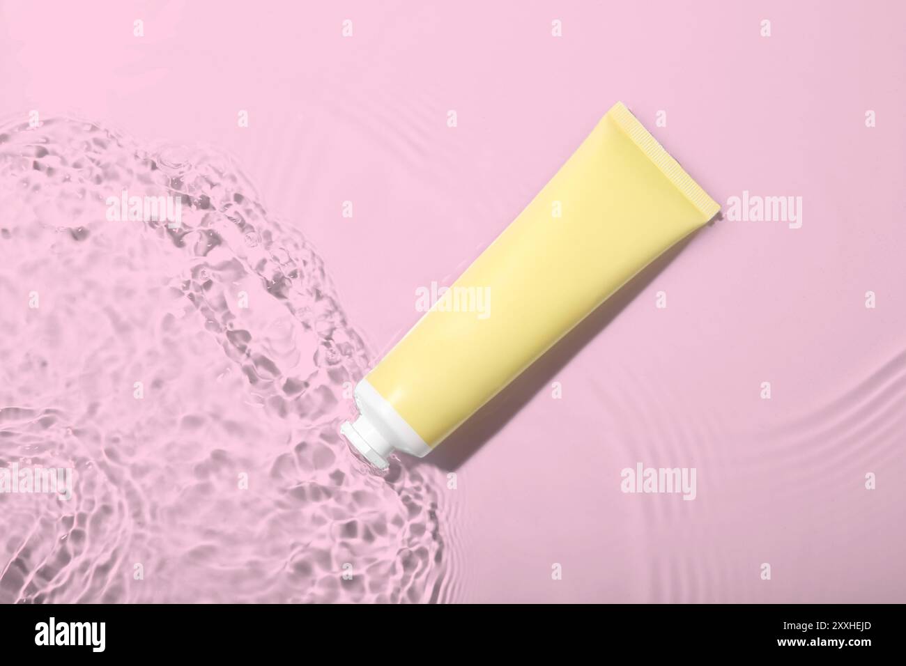 Cosmetic product. Tube with cream in water on light background, top ...