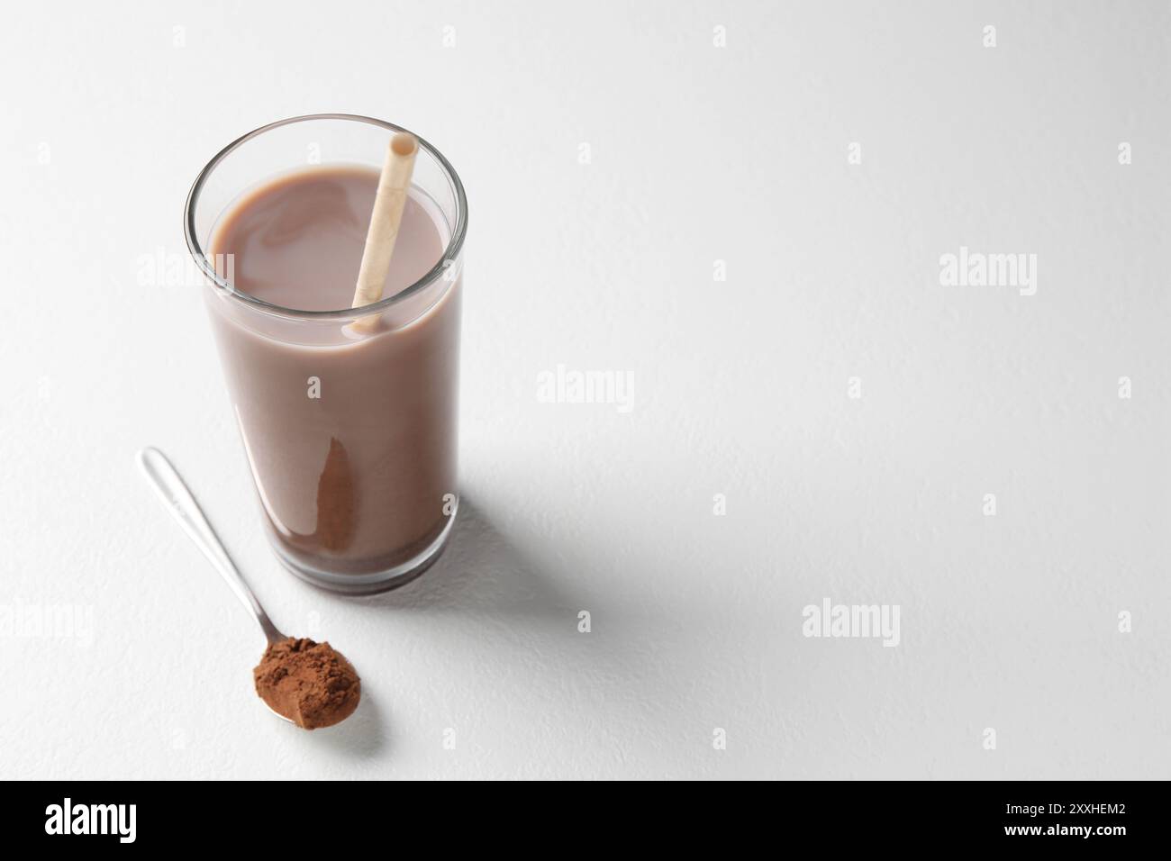 Delicious protein shake in glass and spoon with powder on white ...