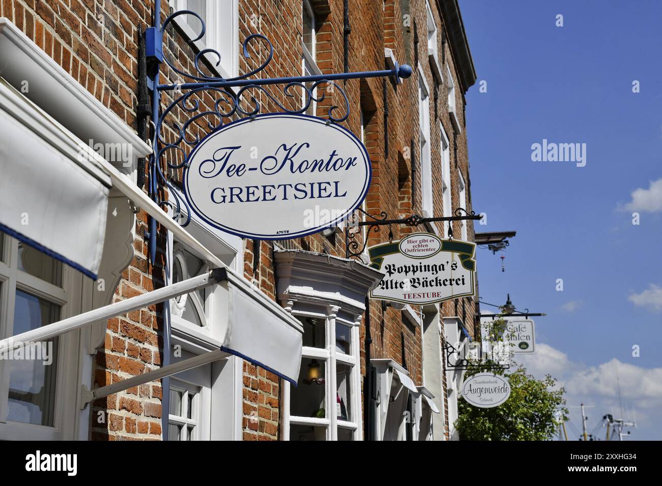 A sign for a tea shop on a traditional brick house under a clear blue ...