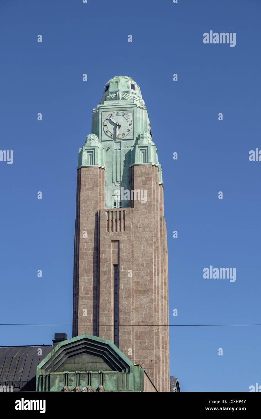 A tall clock tower with a green dome and clock against a clear blue sky ...