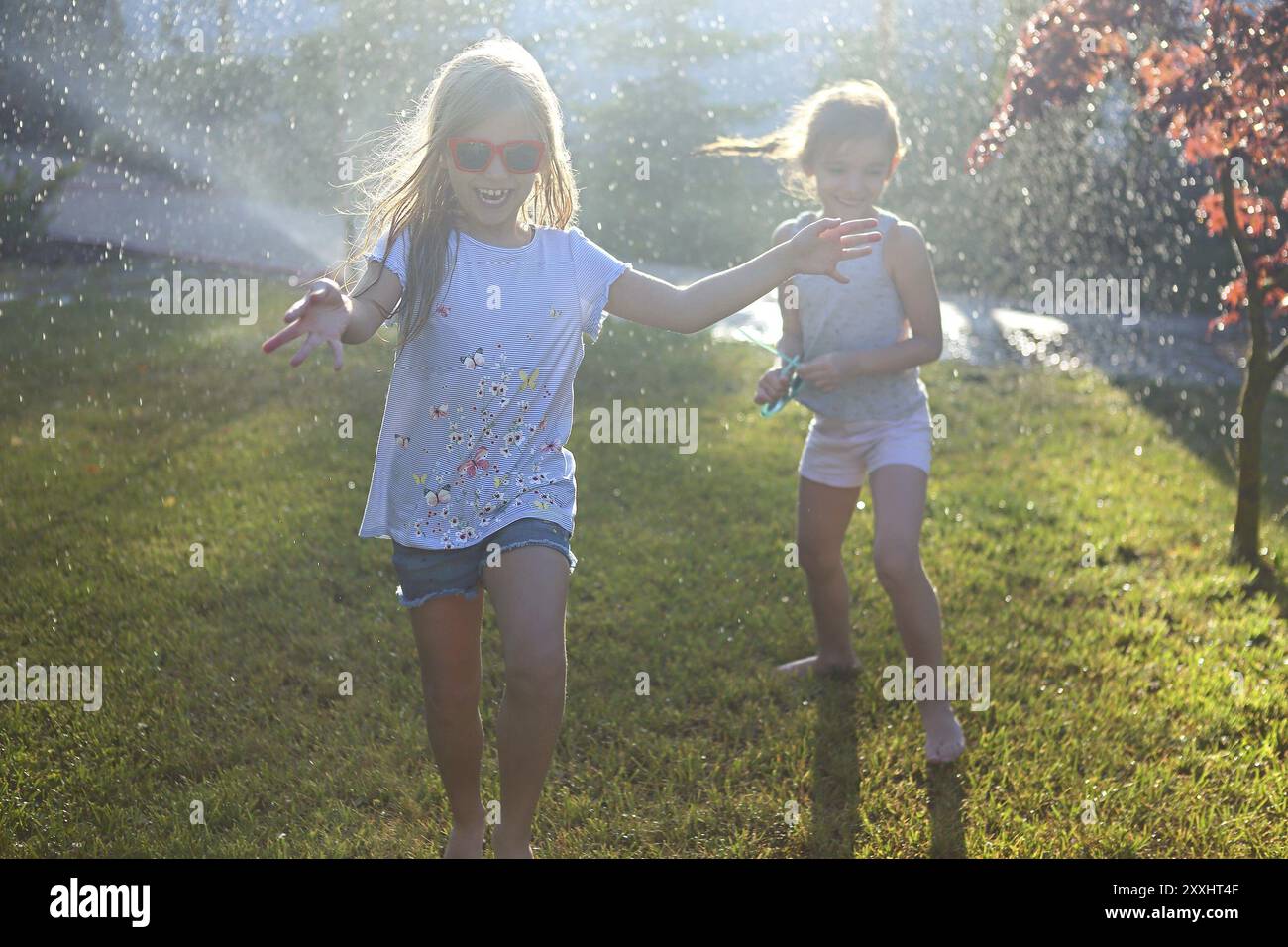 Children playing in sprinkler hi-res stock photography and images - Alamy