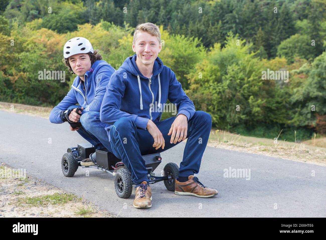 Two young dutch men sitting together on mountainboard in nature Stock ...