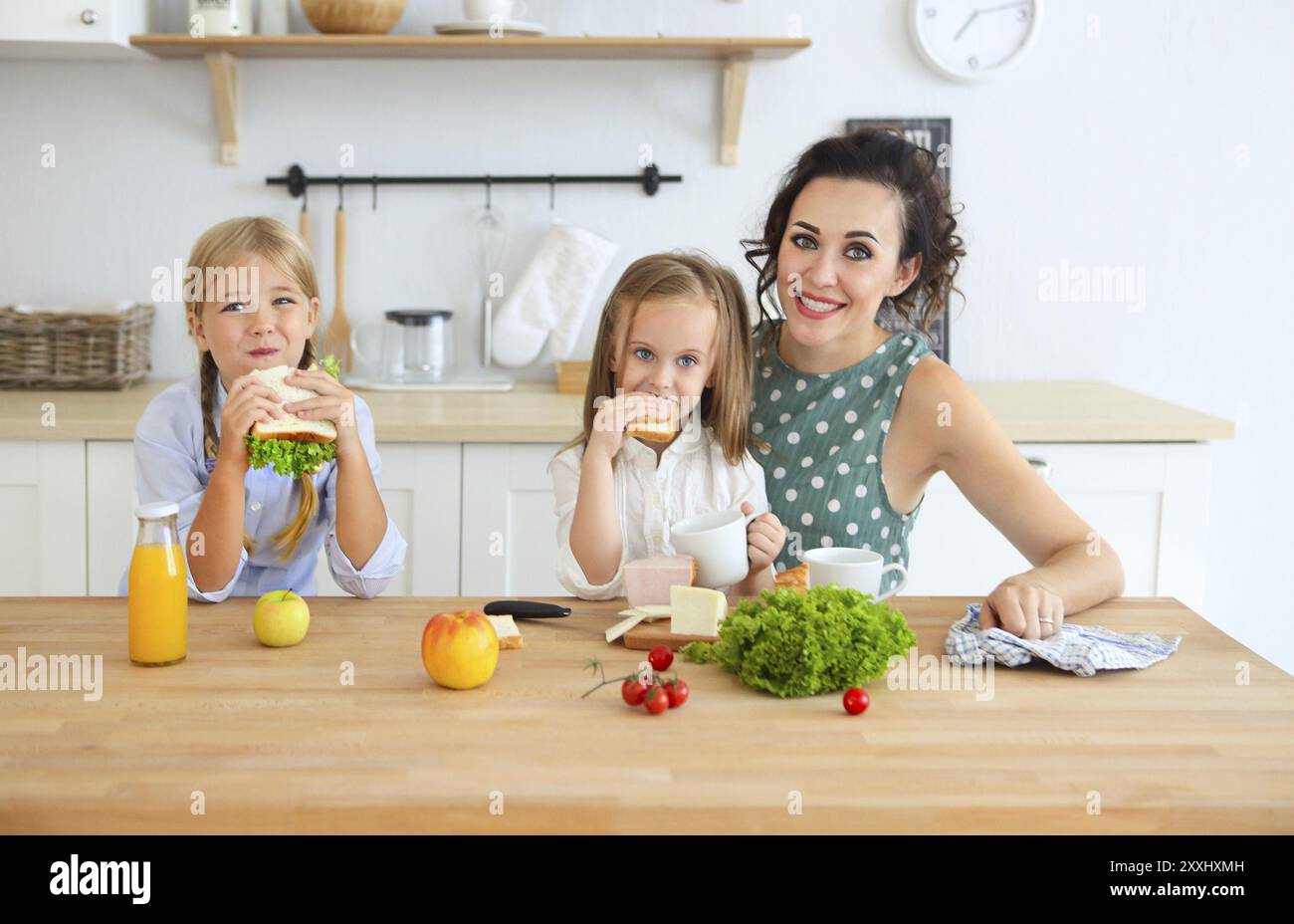 Happy young brunette mother with cute little kids having breakfast at home Stock Photo - Alamy